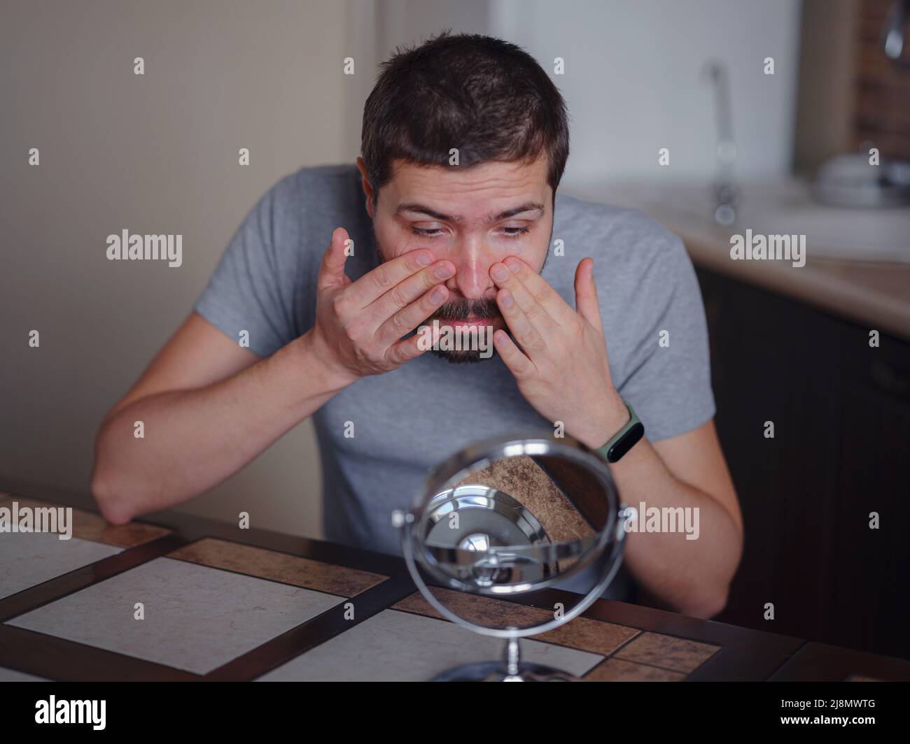 guy checking his skin. Young man looking in mirror touches face with ...