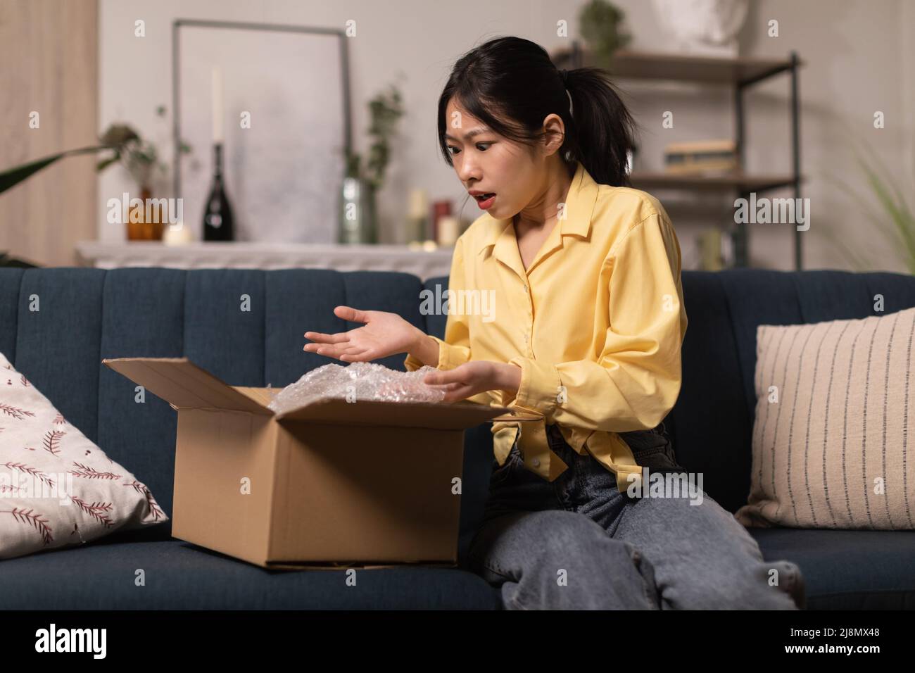 Confused young Asian woman unpacking wrong parcel, delivery mistake ...