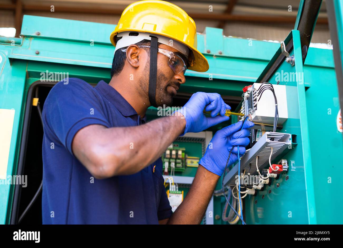young electrical engineer with protective workware repairing or ...