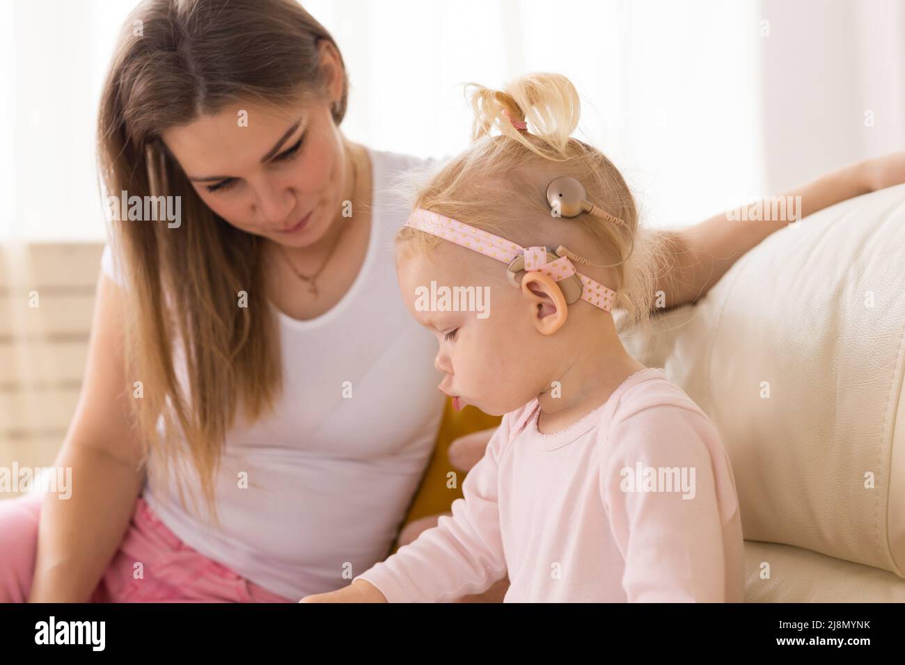 Happy child girl with cochlear implant having fun with her mother ...