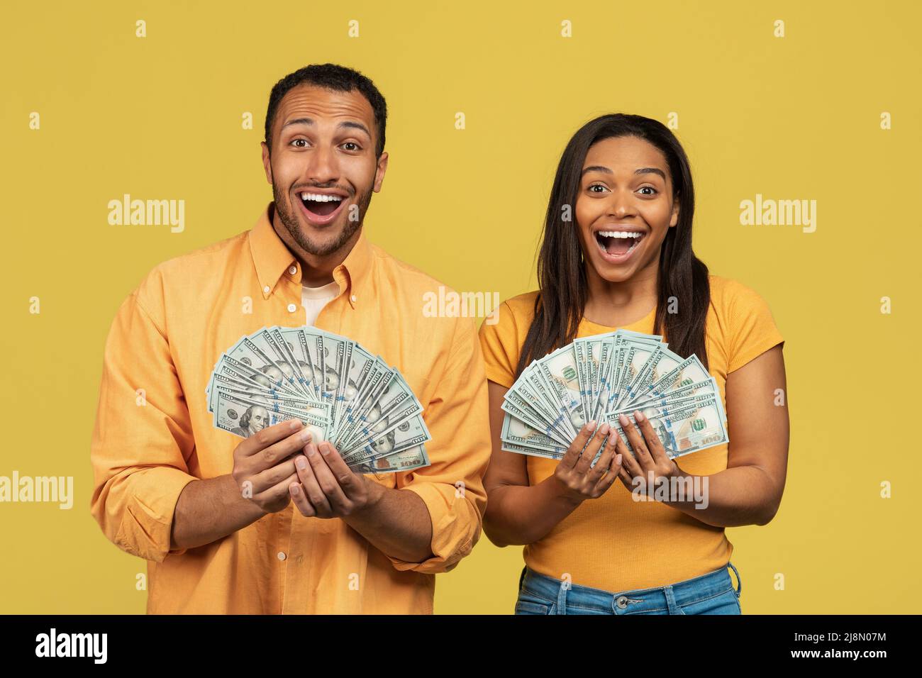 Excited young African American couple holding fans of money, shouting ...