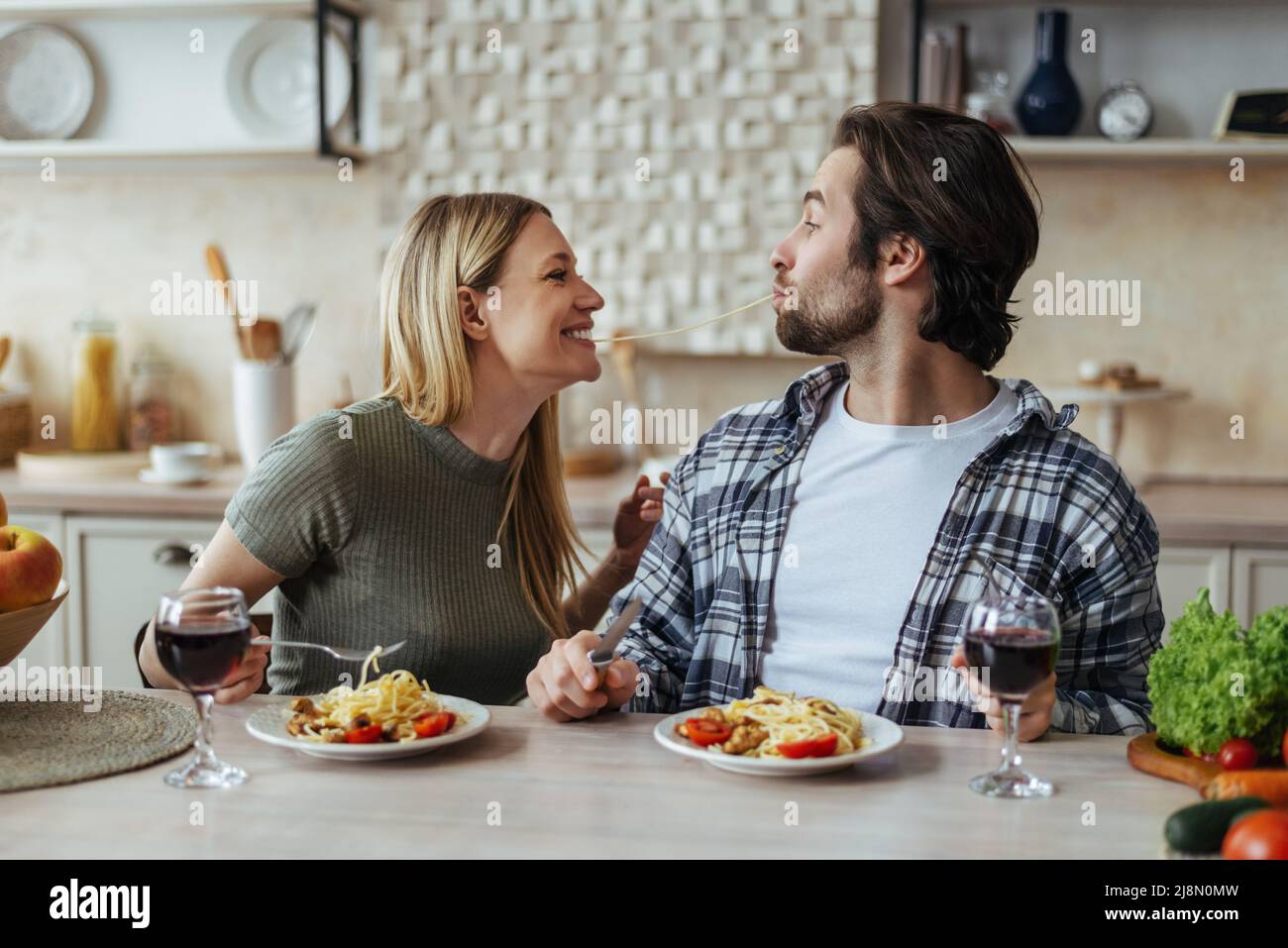 Glad happy handsome caucasian millennial couple eat pasta together ...