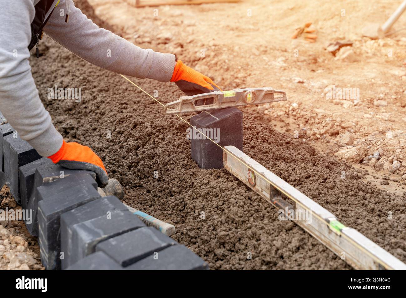 Builder installing paving blocks during road and footpath construction ...