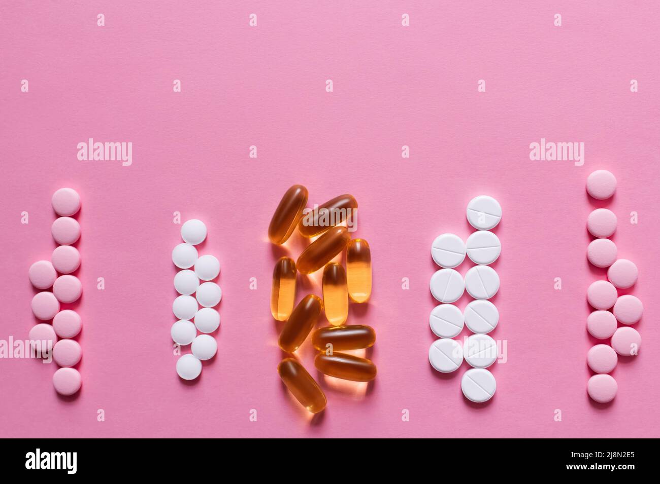 flat lay view of different round shape pills and jelly capsules on pink ...
