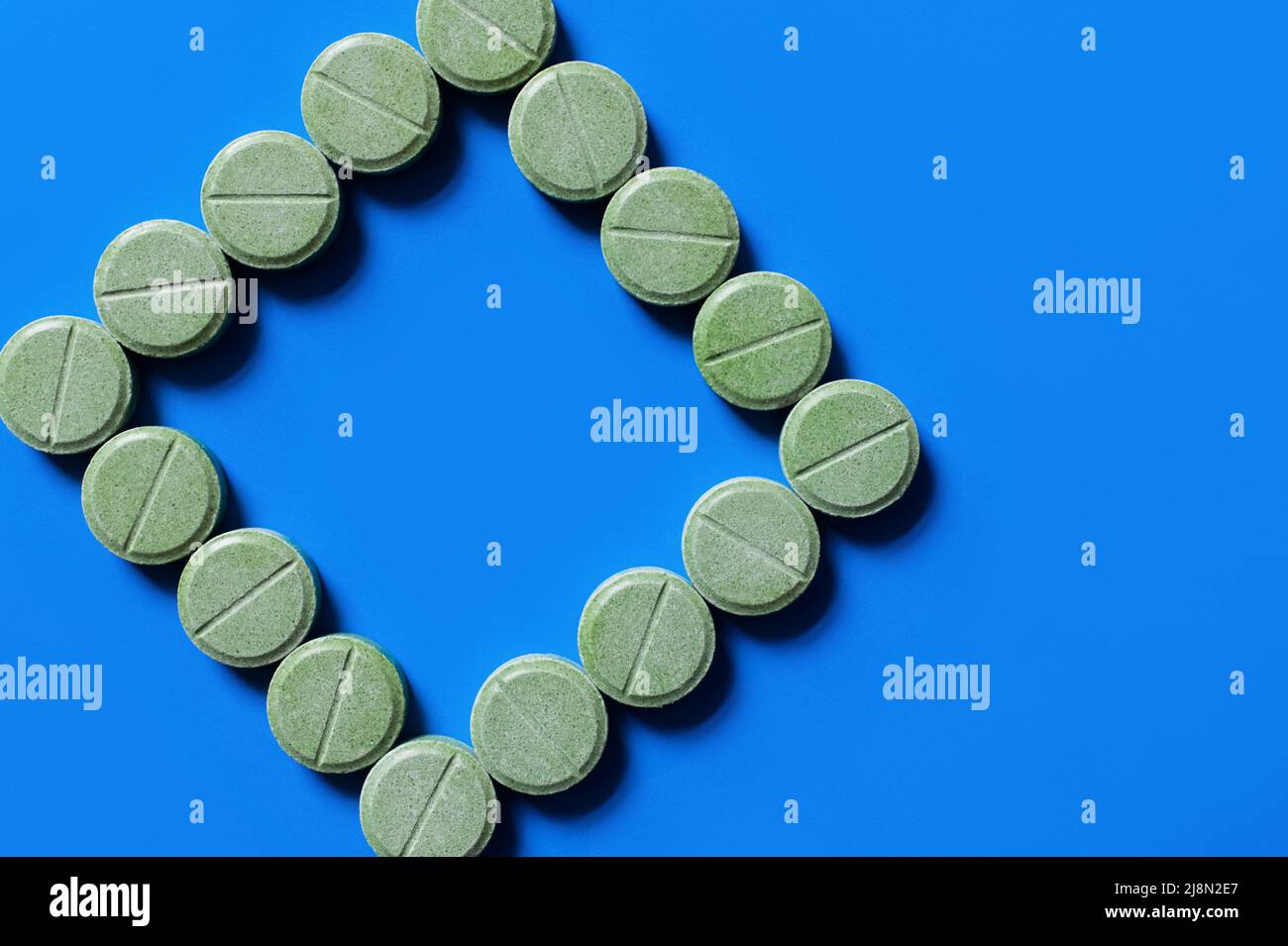 top view of green pills in shape of rhombus on bright blue background ...