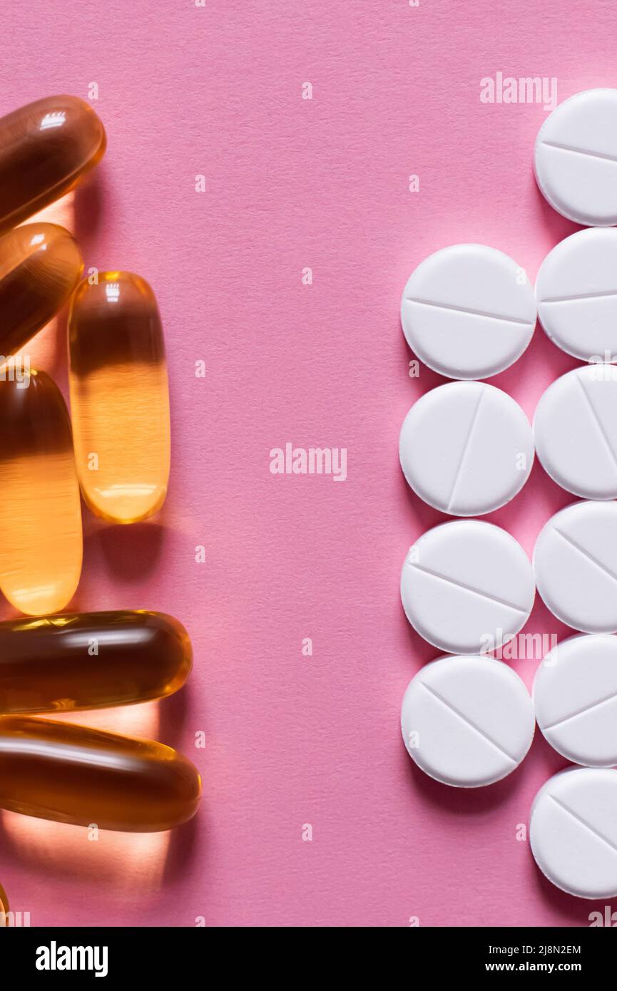 top view of white round shape pills and jelly capsules on pink ...