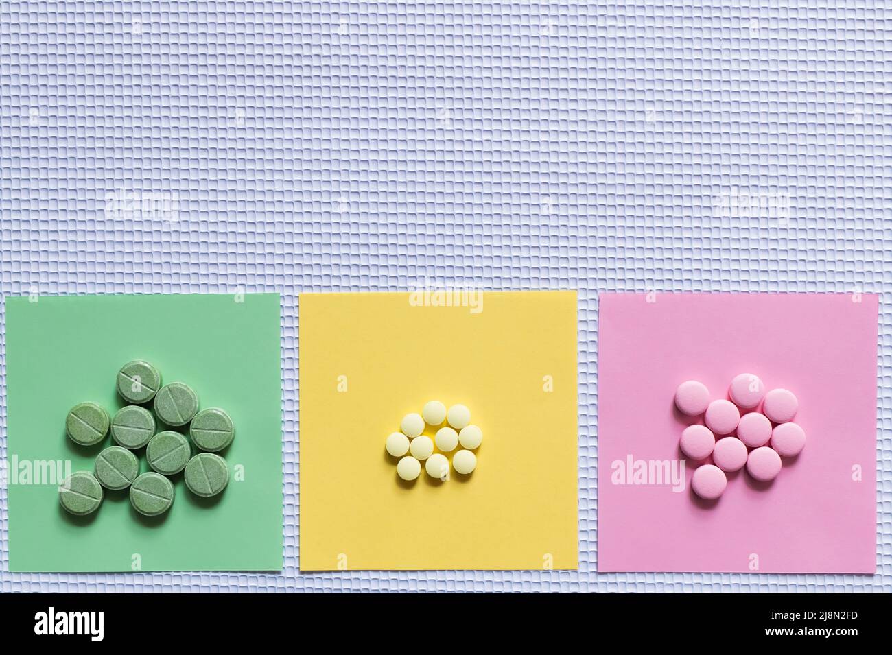 top view of colorful round shape pills on paper notes on textured white ...