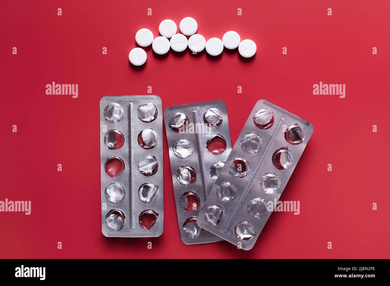 top view of used blister packs near round shape pills on crimson ...