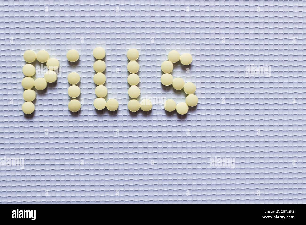 top view of pills word made of yellow round shape medication on white ...