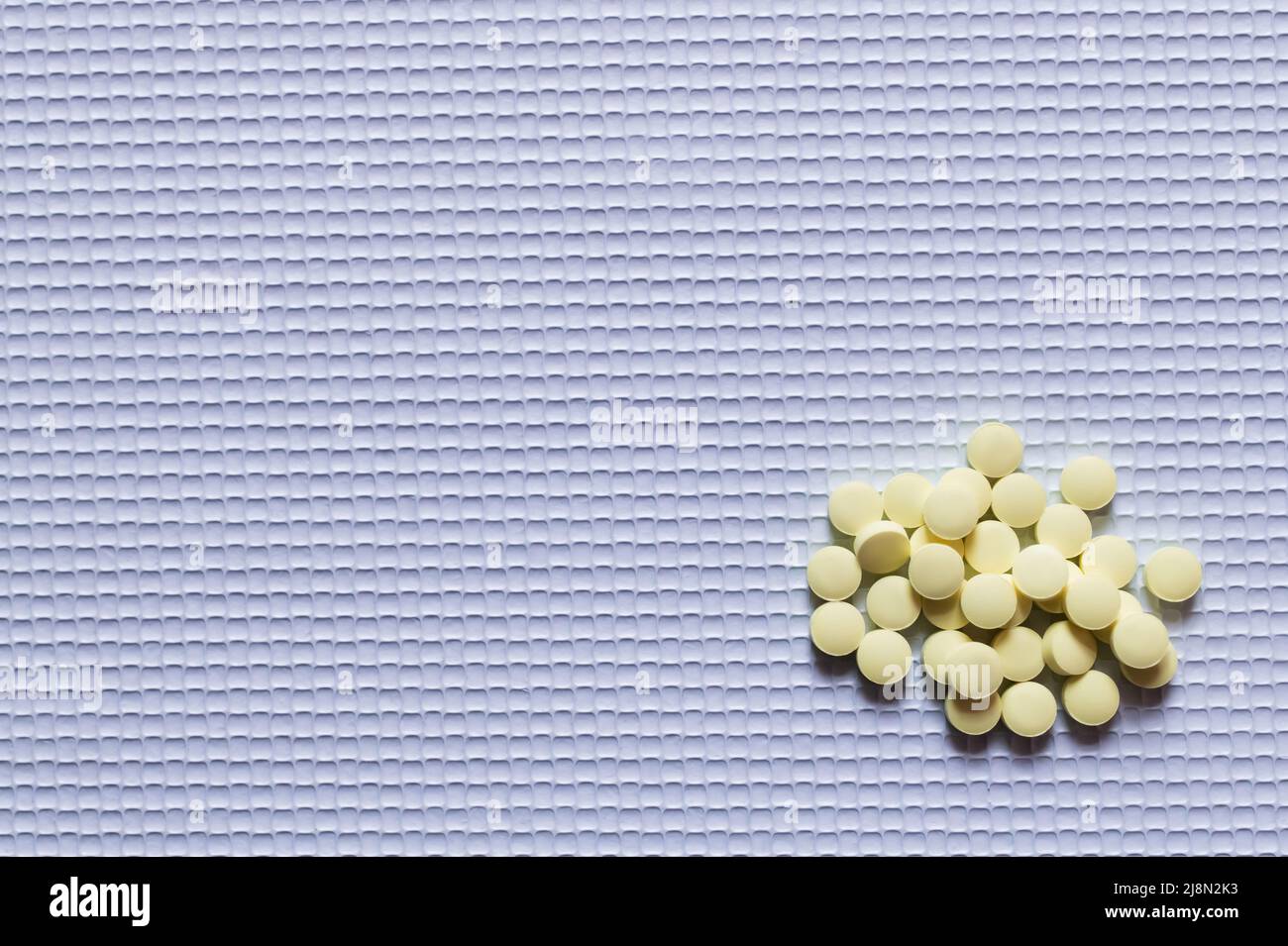 top view of pile with yellow round shape pills on white textured ...