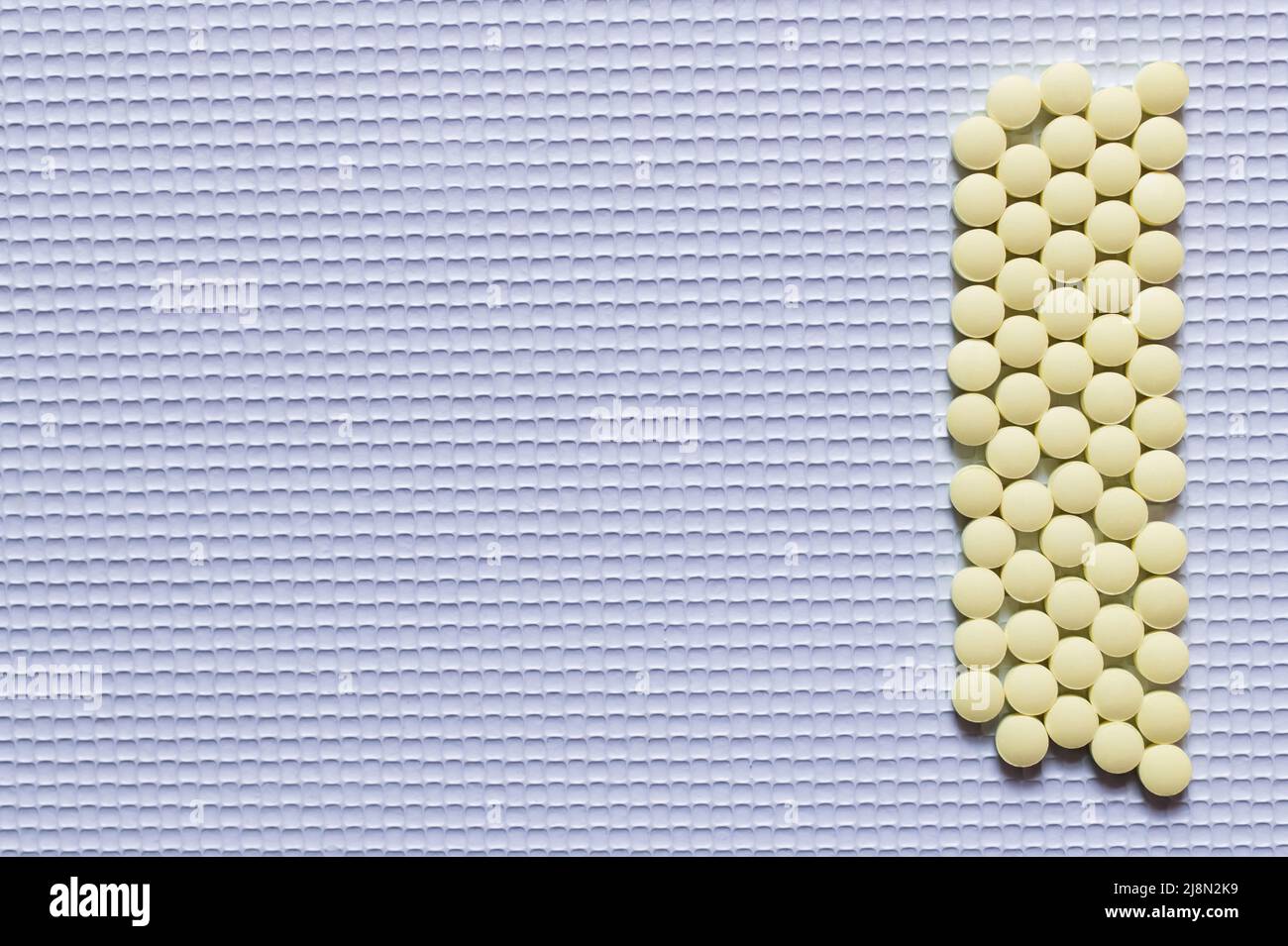 flat lay of yellow round shape medication on white textured background ...