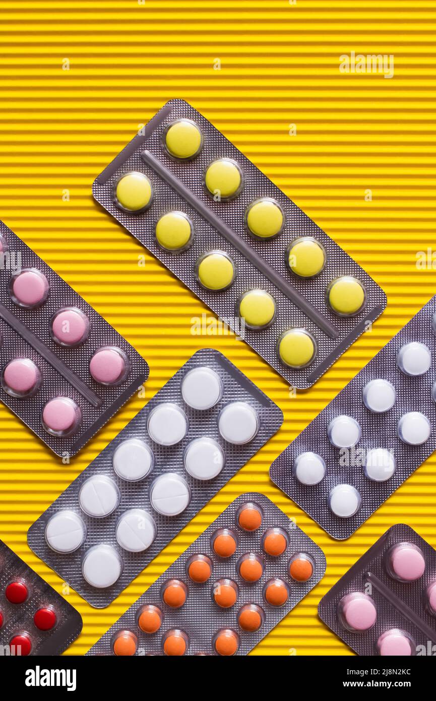 top view of blister packs with different colorful pills on yellow ...