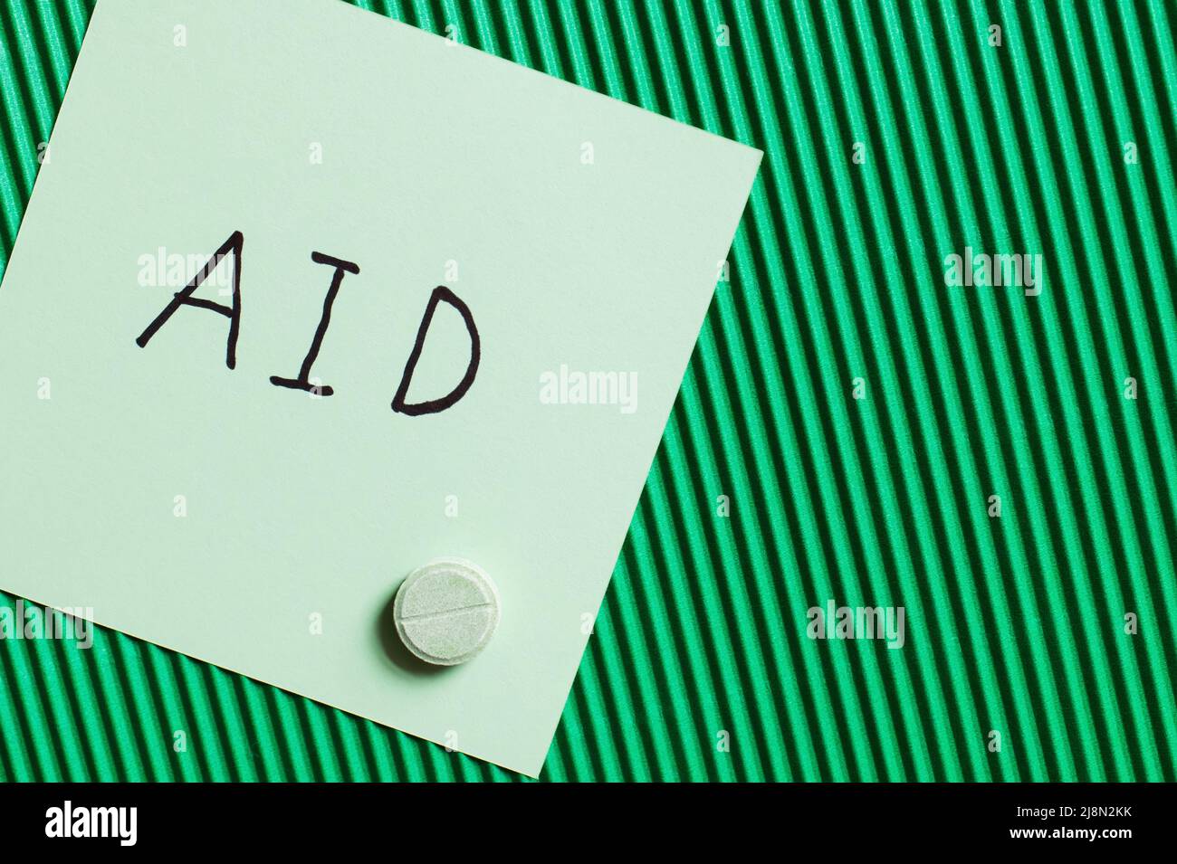 top view of round shape pill near paper note with aid lettering on ...
