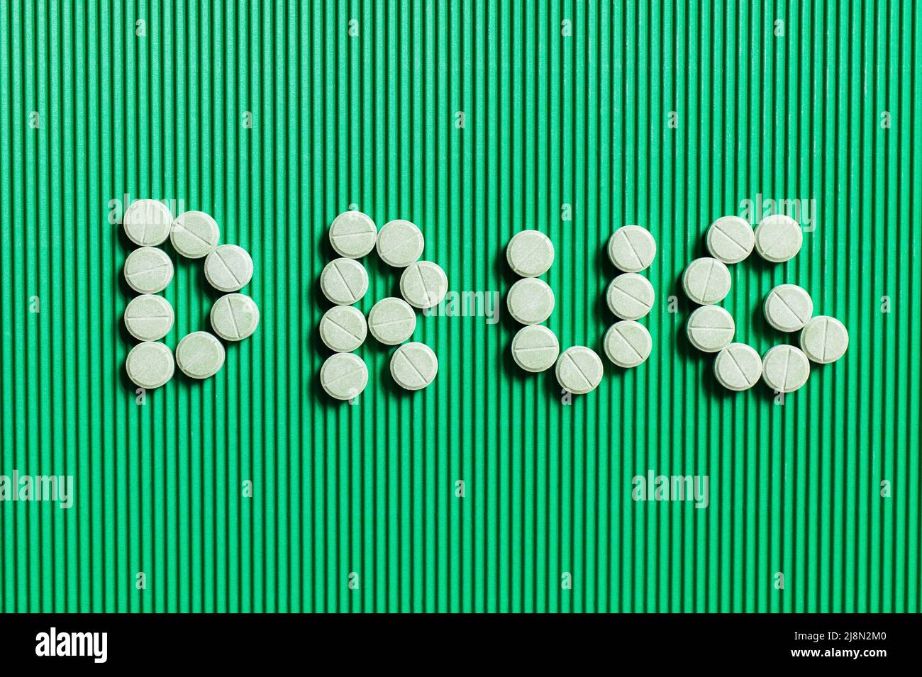 top view of drug word made of yellow round shape medication on green ...