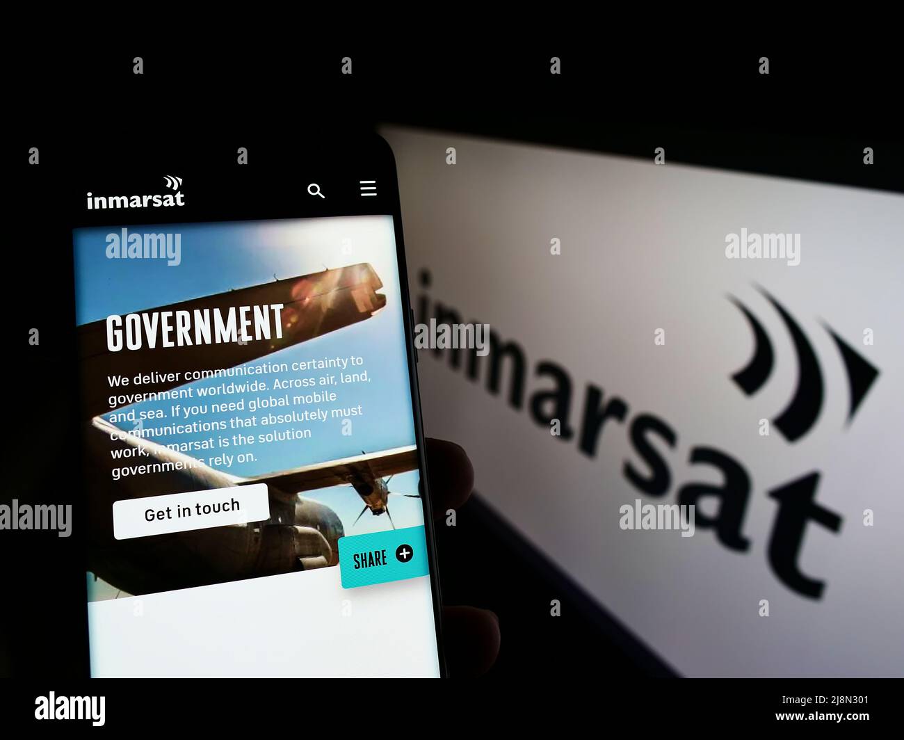 Person holding smartphone with webpage of satellite company Inmarsat ...