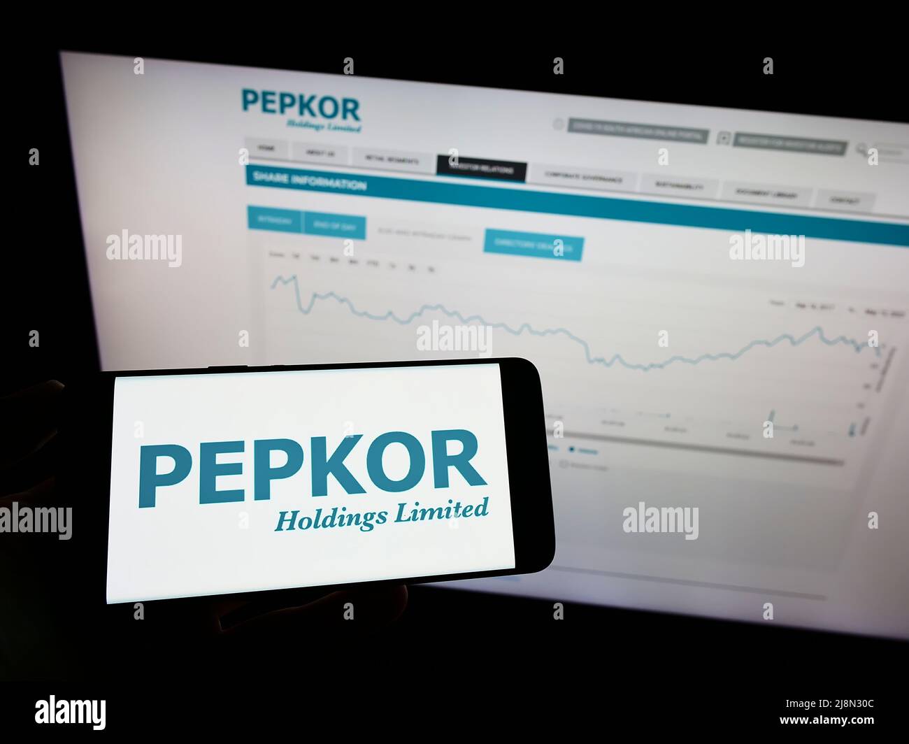 Person holding mobile phone with logo of South African company Pepkor Holdings Limited on screen ...