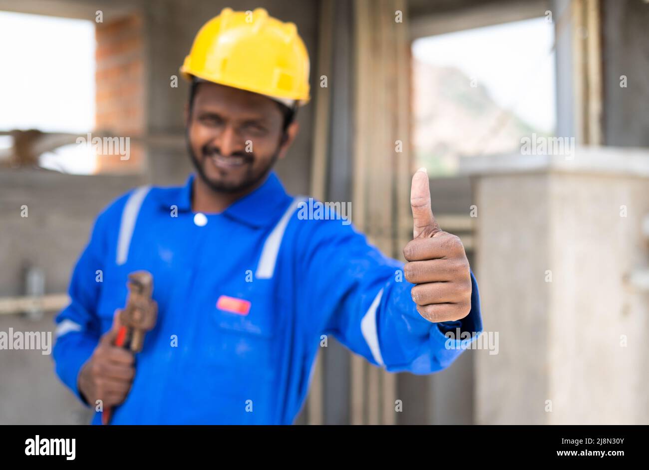plumber with pipe and plumbing tool in hand showing thumb by looking at ...