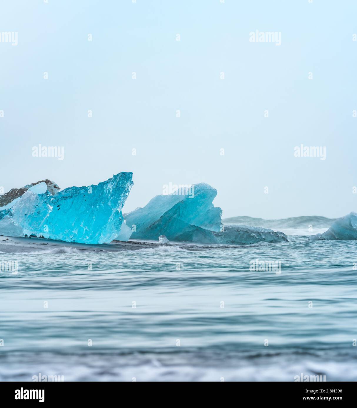 Deep blue icebergs over the black sand beach under white sky Stock ...