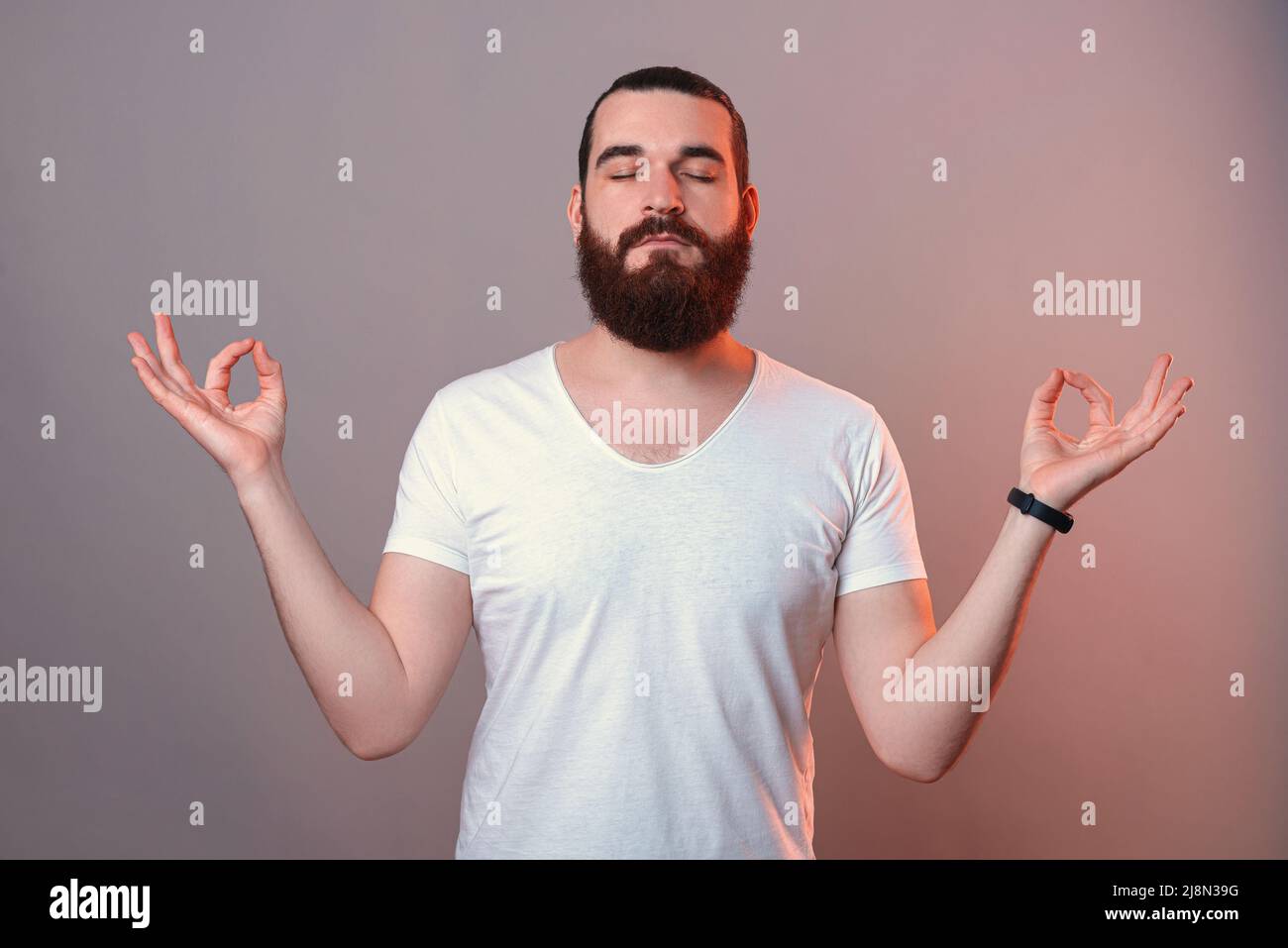 Bearded man with closed eyes is making the zen gesture in a studio with ...