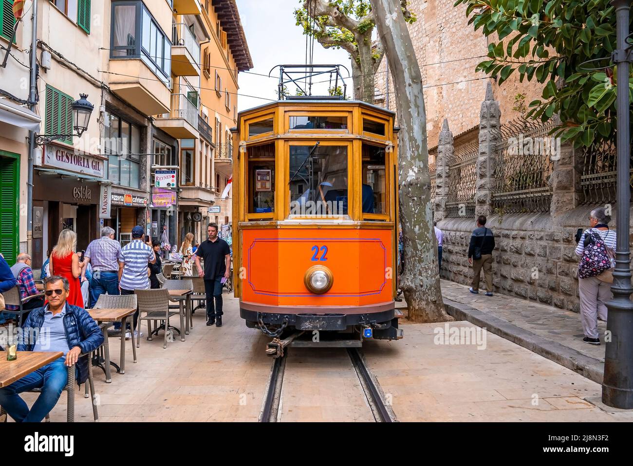 Orange tram moving on rail tracks amidst buildings in city during ...