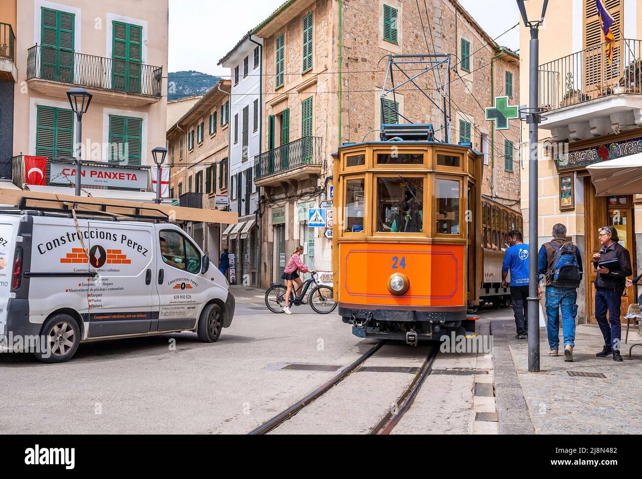 Traditional tram moving on rail tracks by tourists amidst buildings in ...