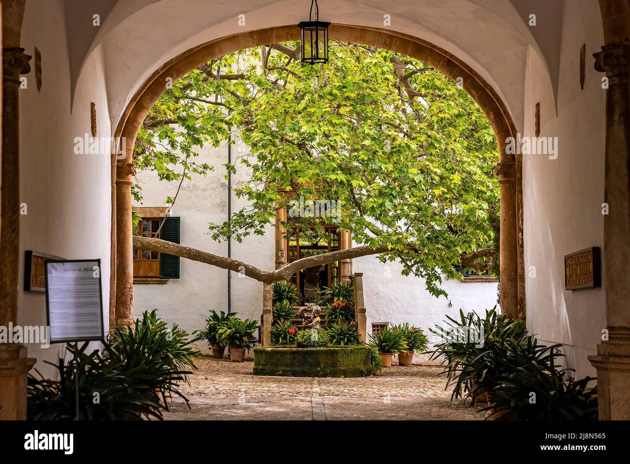 Arch entrance of historic building with signboard and trees in city ...