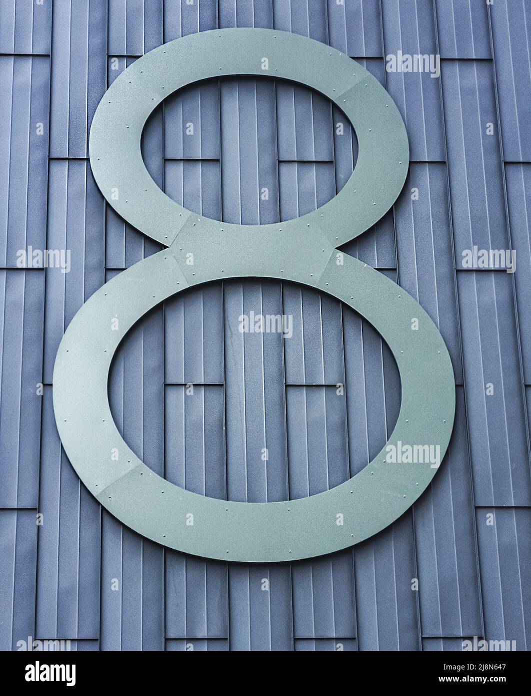 Numeral 8 eight on a gray background of the facade of the building ...
