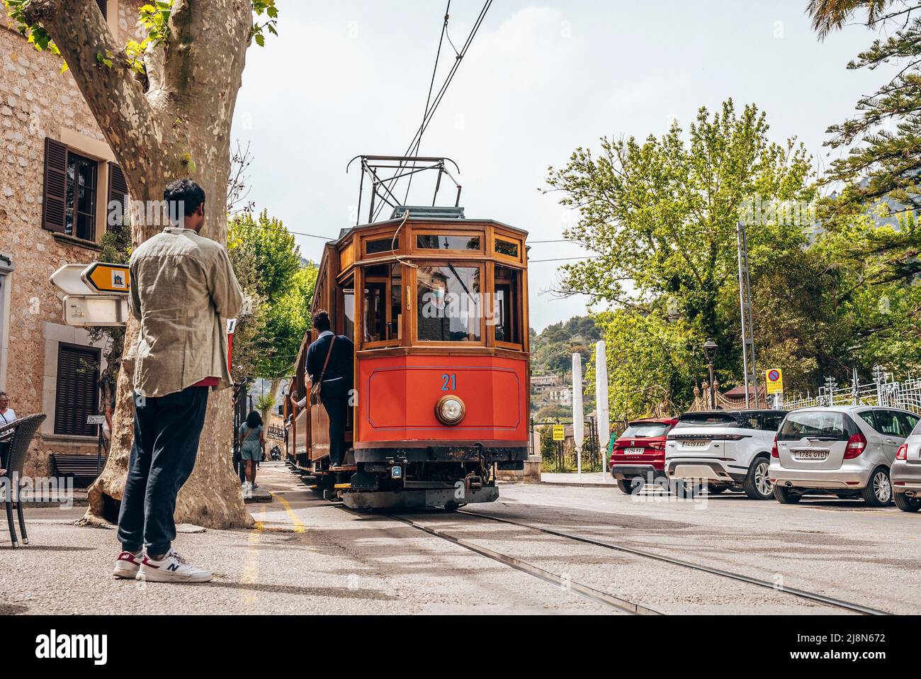 Orange tram waiting for passengers on rail tracks by buildings against ...