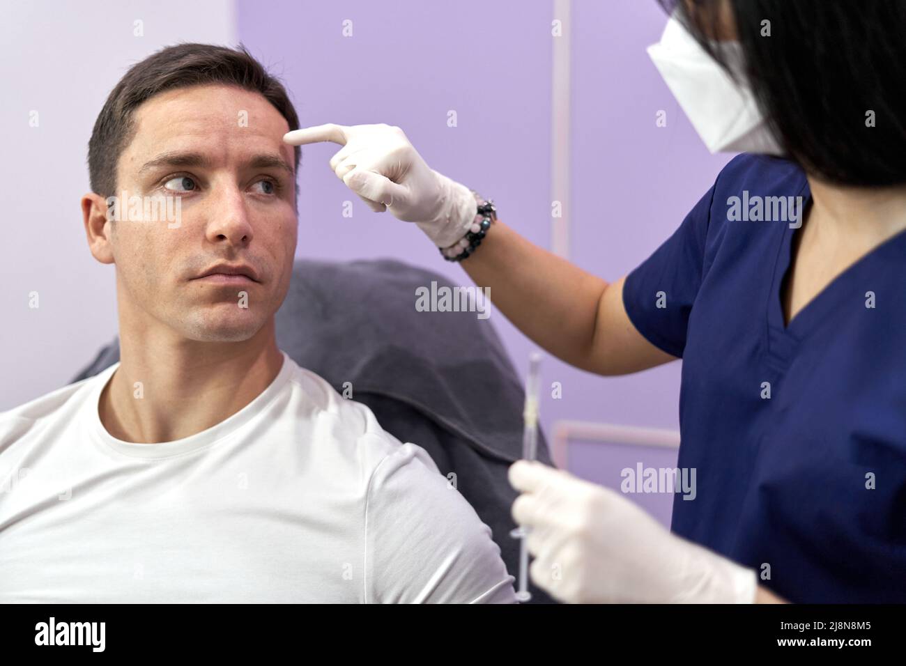 Doctor pointing to the spot she will inject a botox injection into a ...