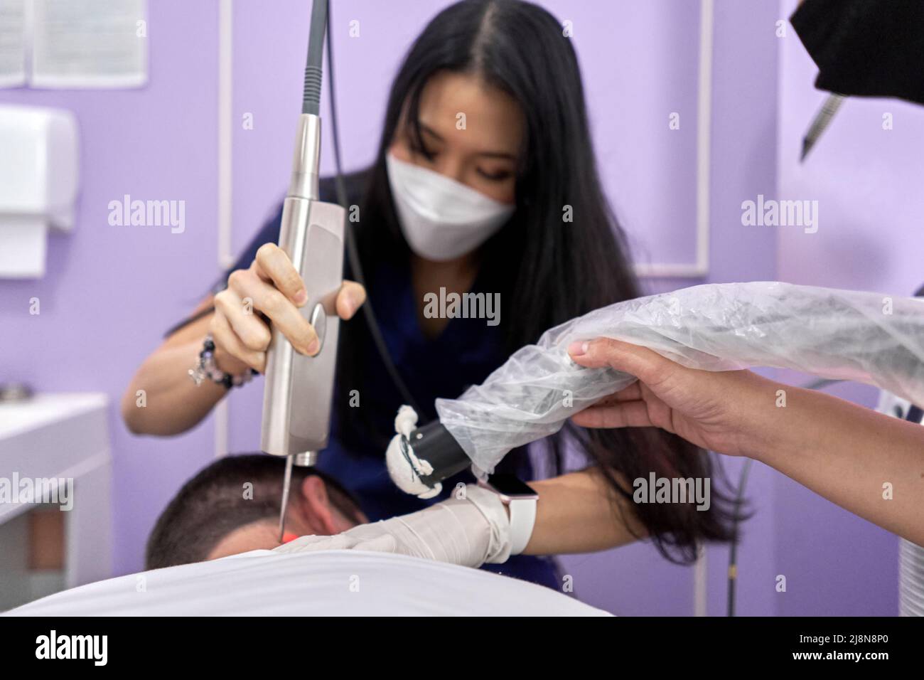 Staff of a clinic applying laser to a patient to perform a beauty skin ...