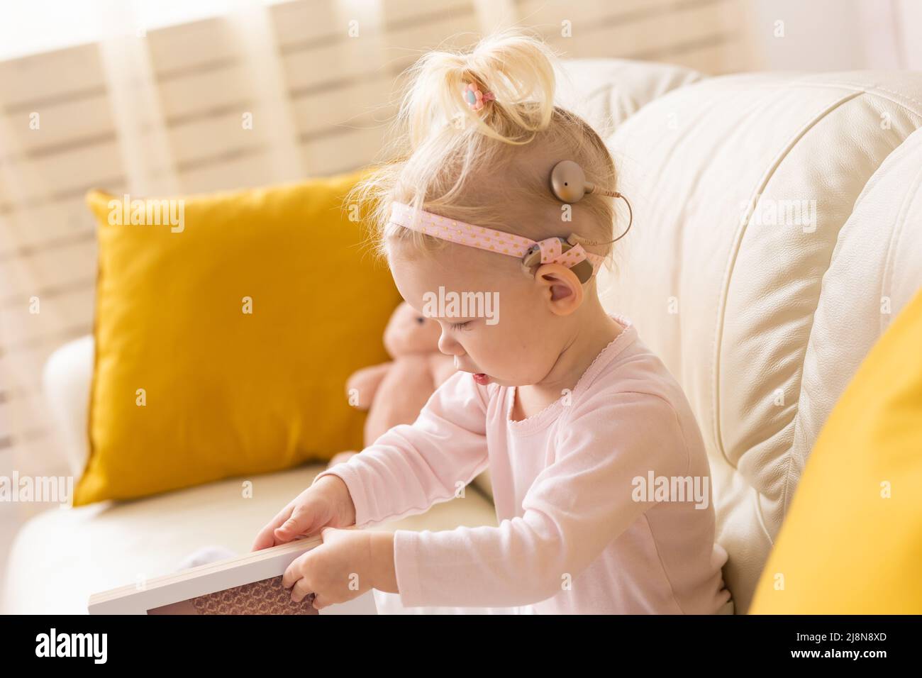 Cochlear implant for baby. Deaf child with hearing aid plays in living ...