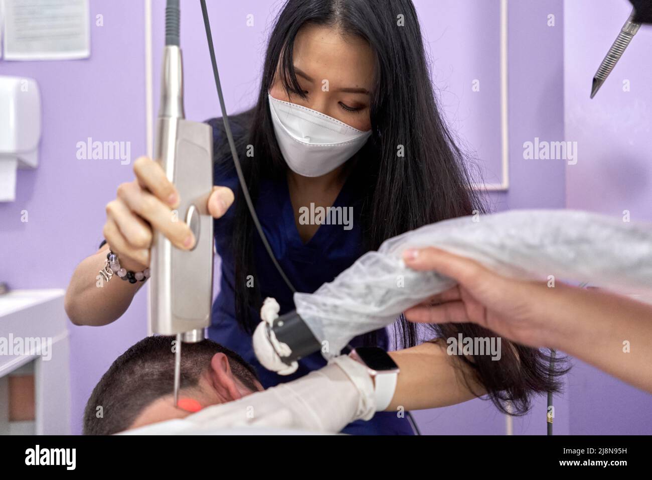 Doctor of a clinic applying laser to a patient to perform a beauty skin ...