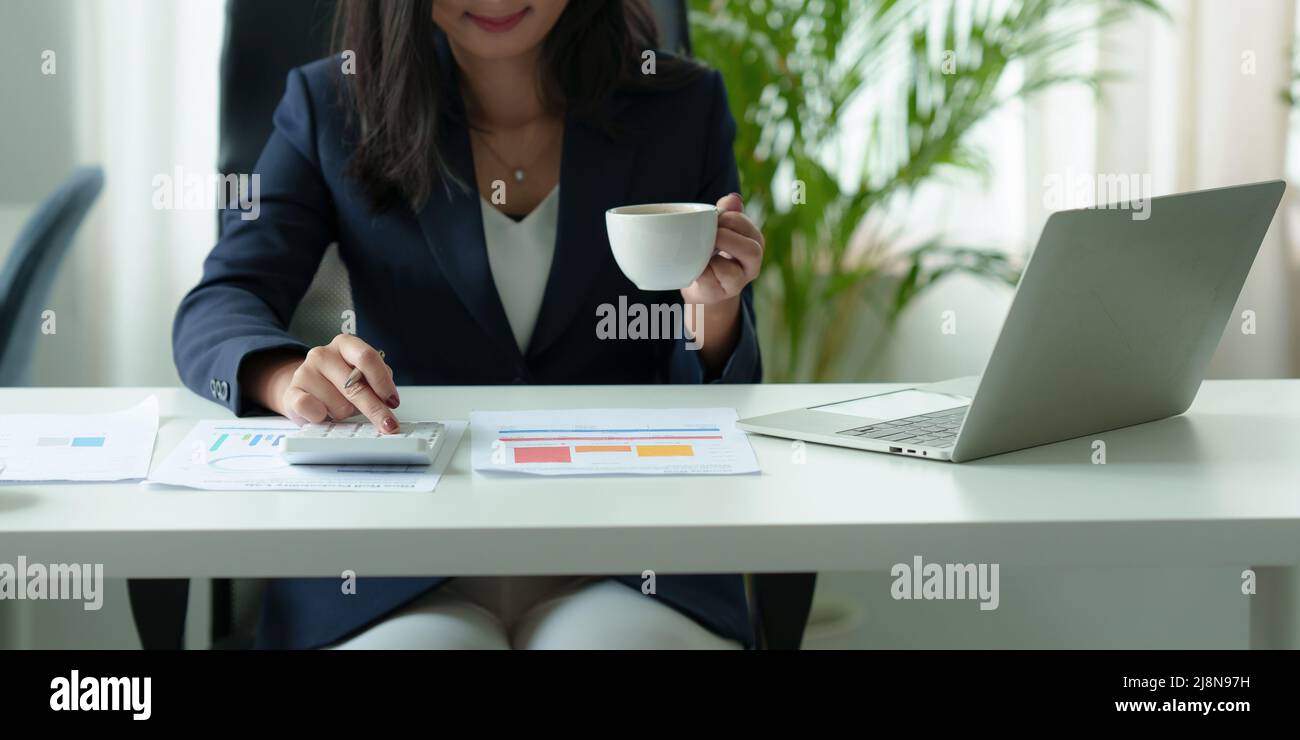 Asian Business Woman or Accountant do math and analyze with calculator ...