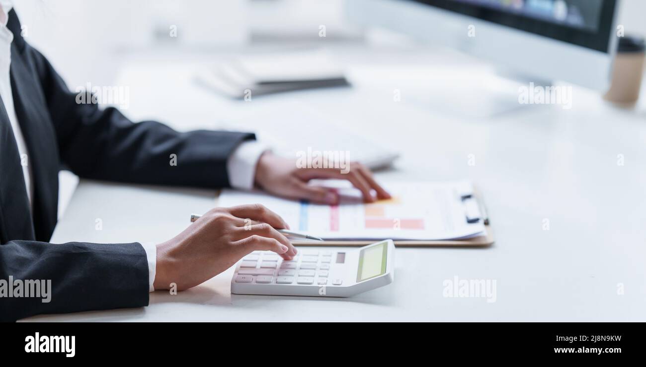 Asian Business Woman or Accountant do math and analyze with calculator ...