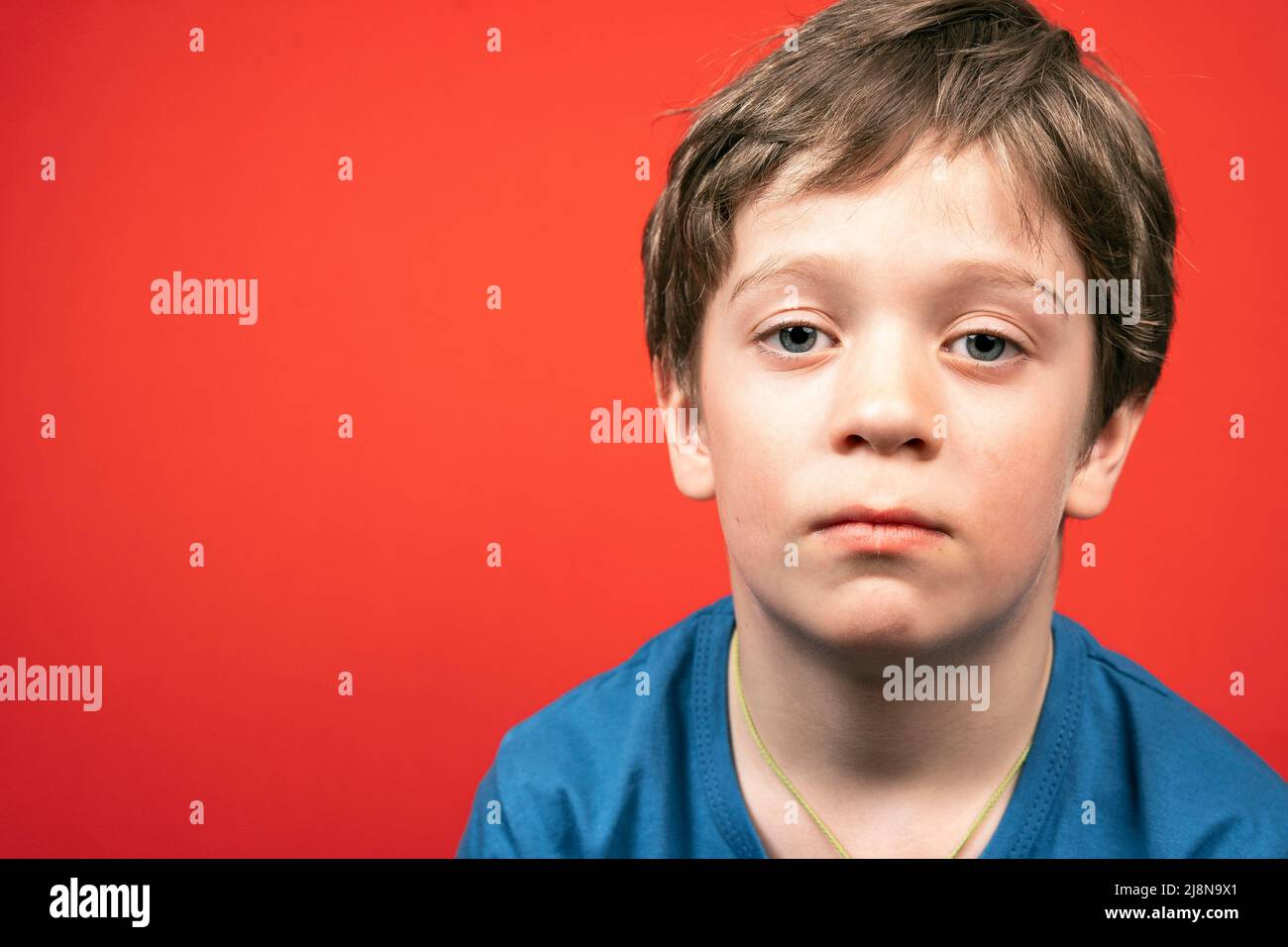 portrait of a sad Caucasian boy of preschool age on a red background ...