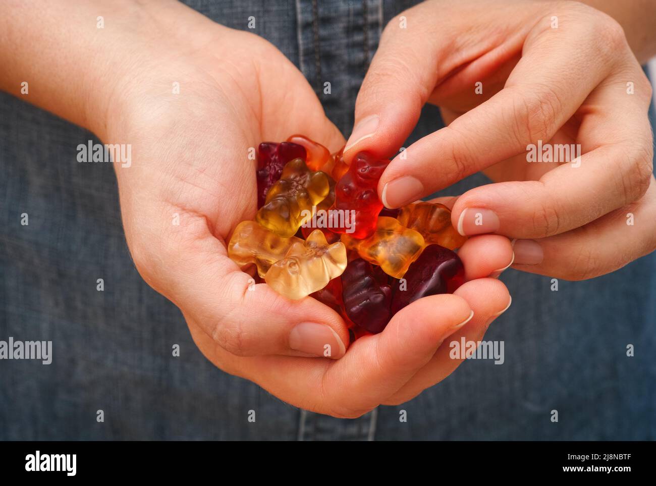 Woman hand taking a Gummy bear candy from her palm full of Gummy bears ...