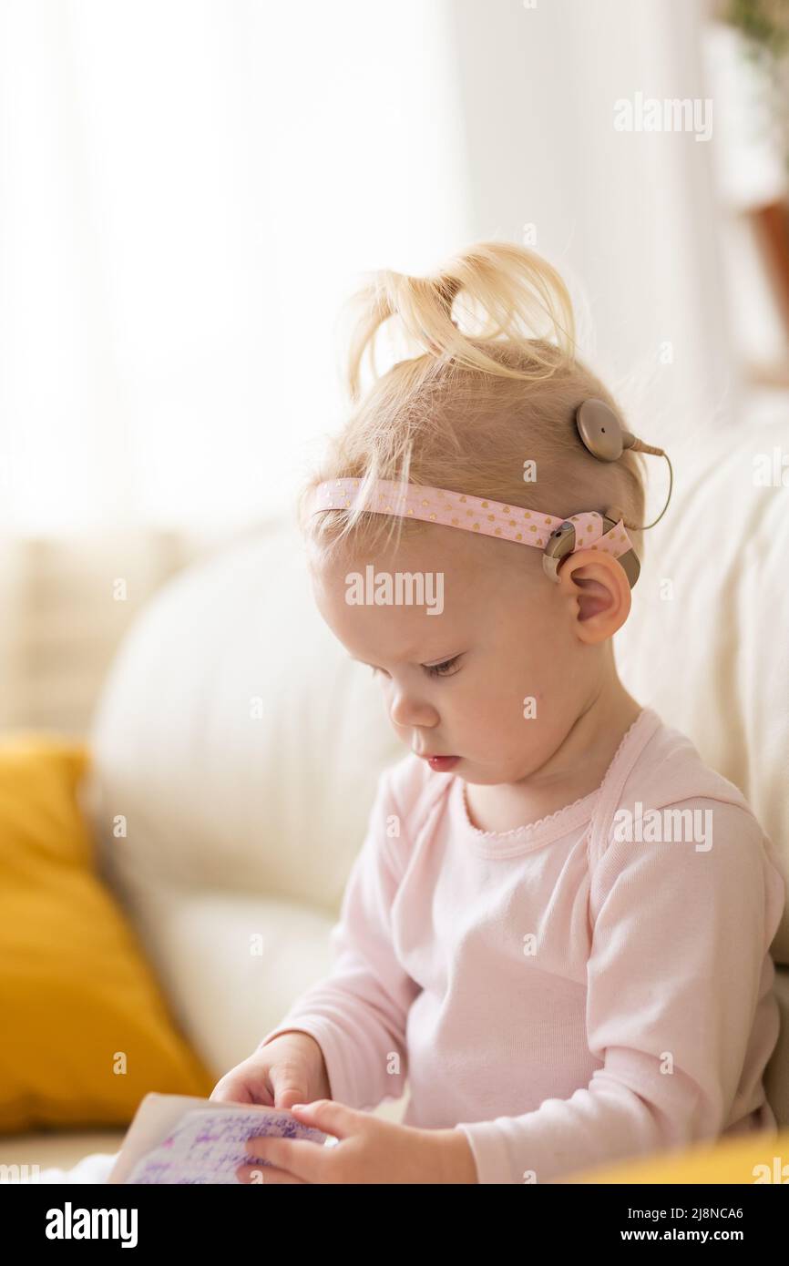 Cochlear implant for baby. Deaf child with hearing aid plays in living ...