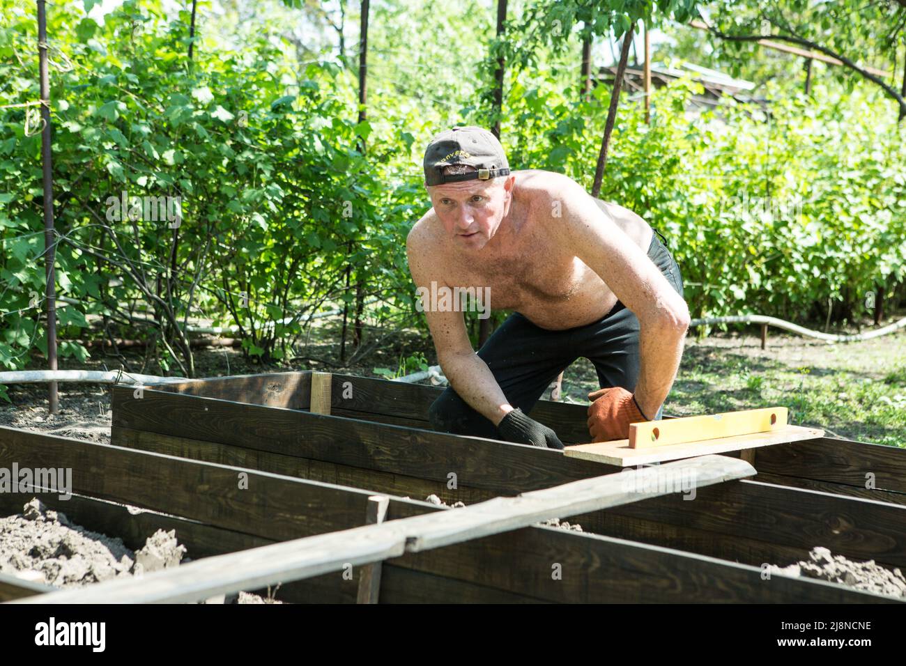 A man of mature years makes high beds on a personal plot. The master ...