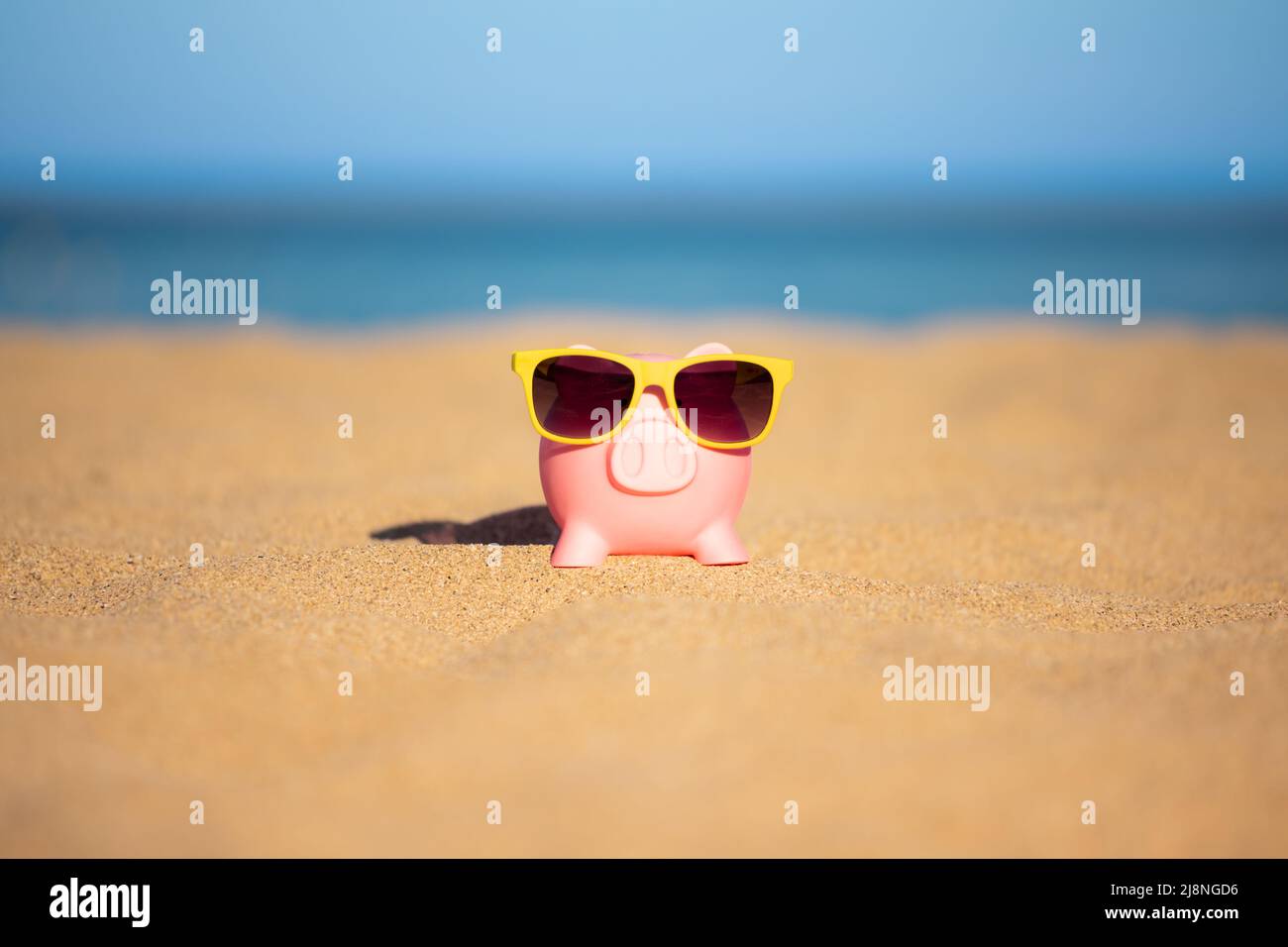 Piggybank on the beach against sea and sky background. Savings for ...