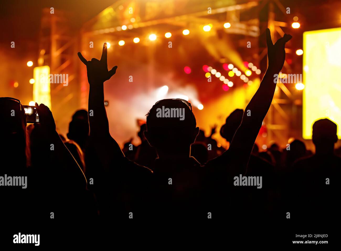 Men and women with raised hands at a concert event Stock Photo - Alamy