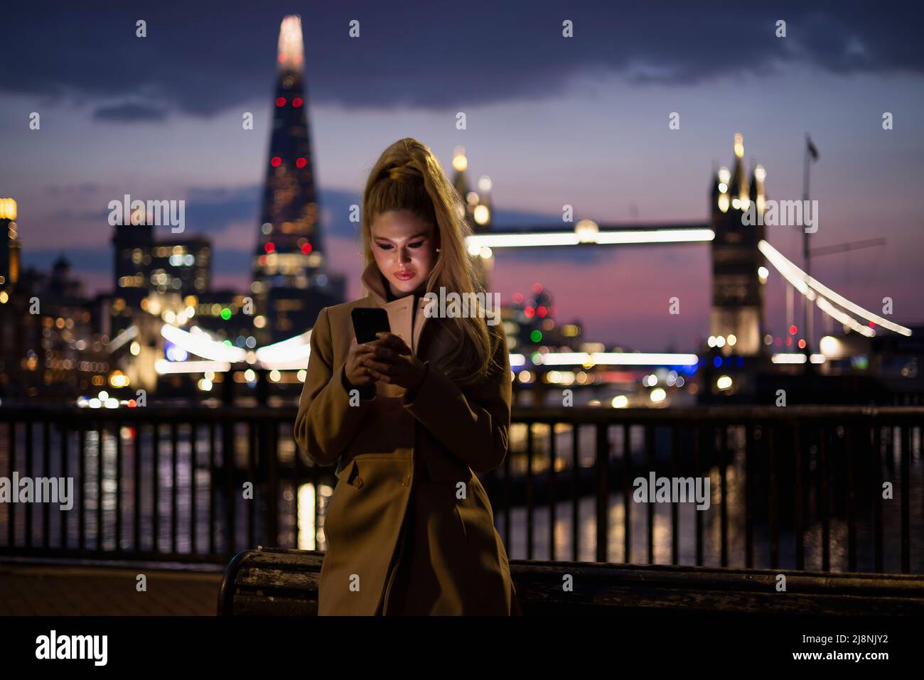 A pretty city woman looks at her smartphone during night time Stock ...