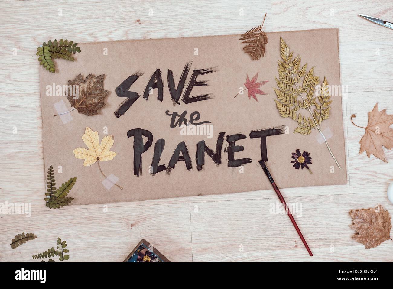 Cardboard of save the planet written with a brush, with leaves and ...