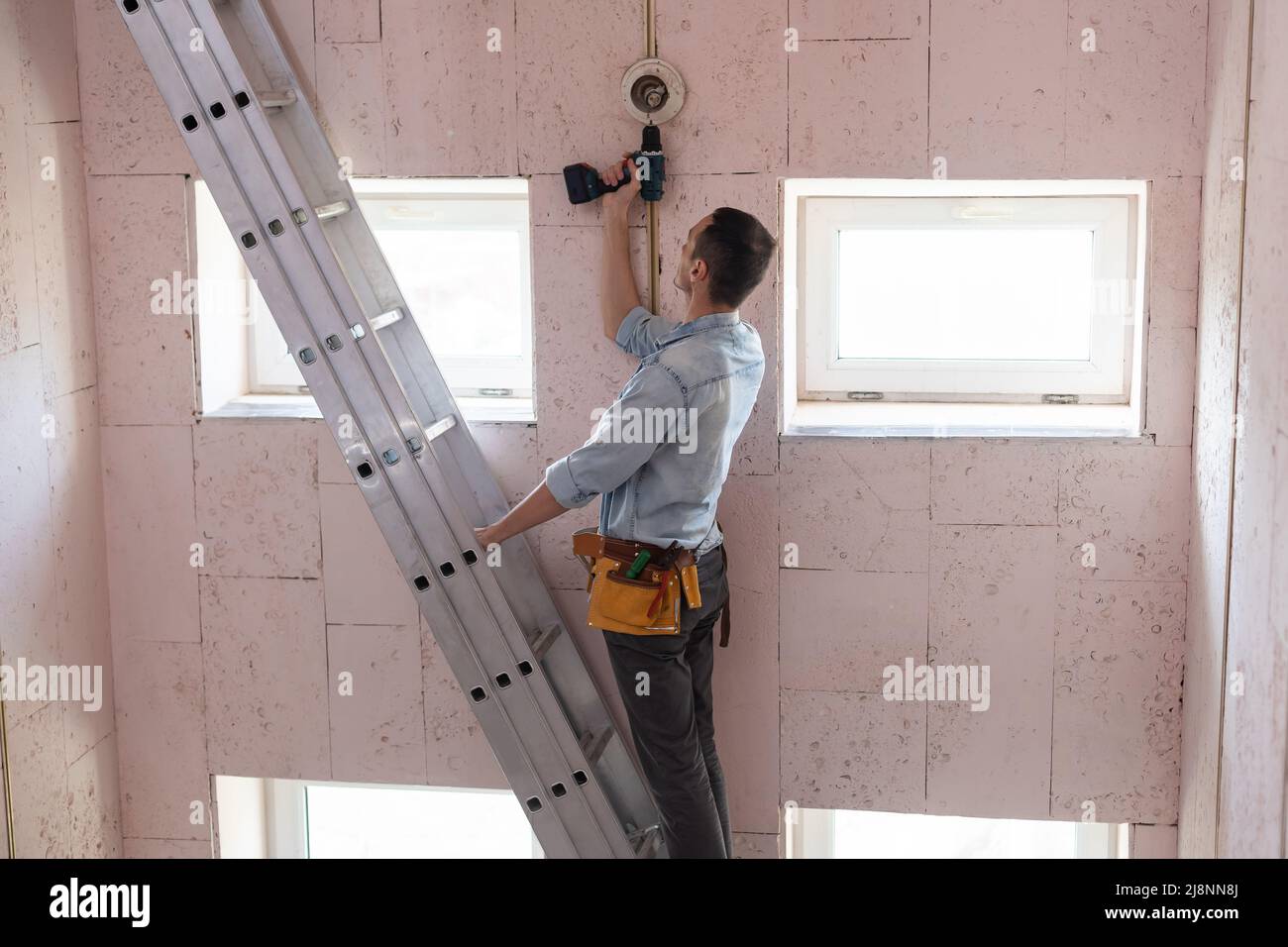 An electrician fixing wires, installing light on the ceiling Stock ...