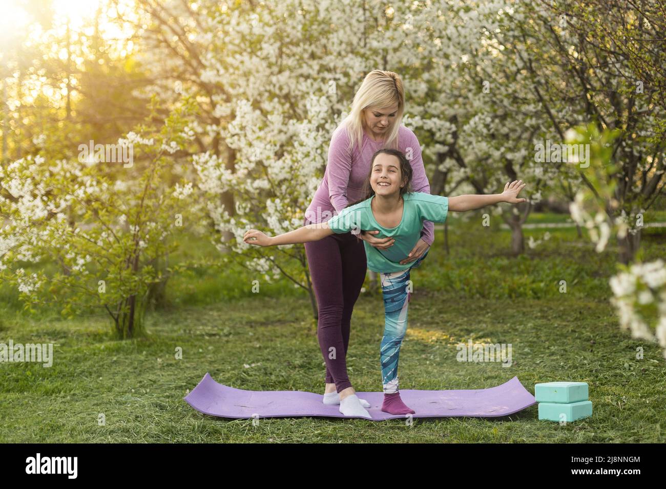 Young sports mother doing physics exercise outdoors in garden near her ...