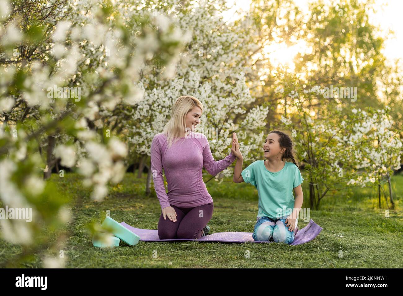 Young sports mother doing physics exercise outdoors in garden near her ...