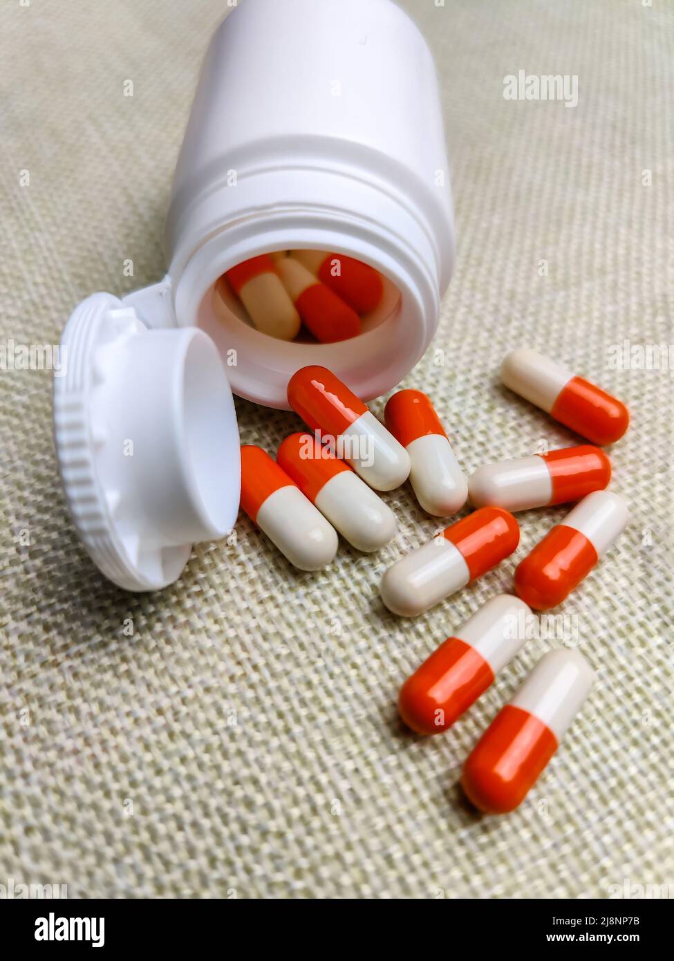 Two-color medicinal capsules in gelatin shell spilled out of plastic ...