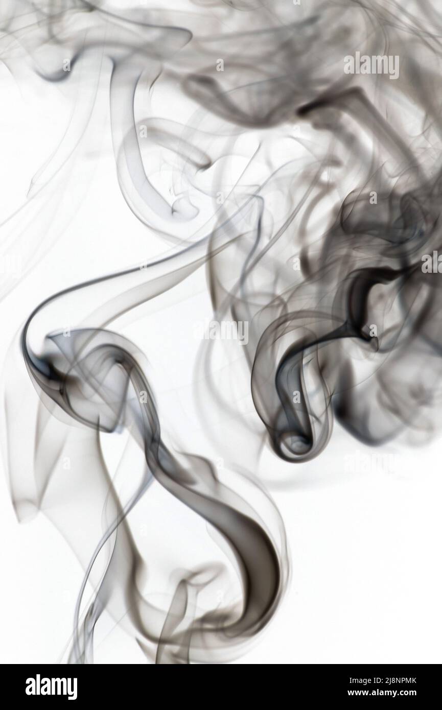 Puffs and curls of dark smoke on a white background rising from a ...