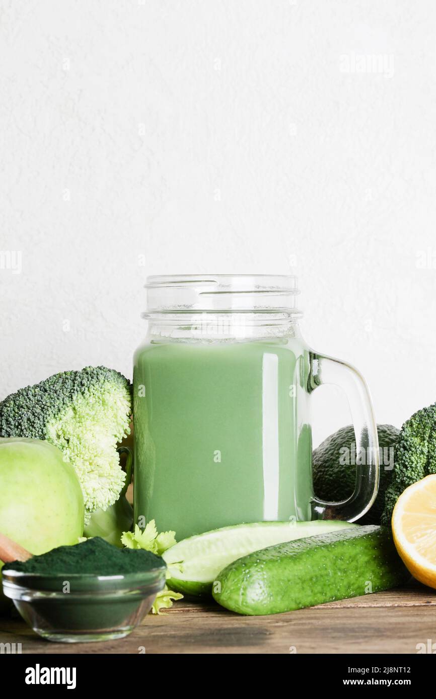 green smoothie in glass bottle, spirulina powder, vegetables and fruits ...