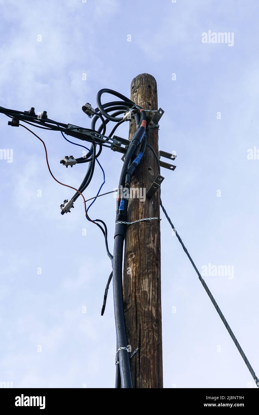 wooden electric pole with attached wires and cables on a blue sky ...