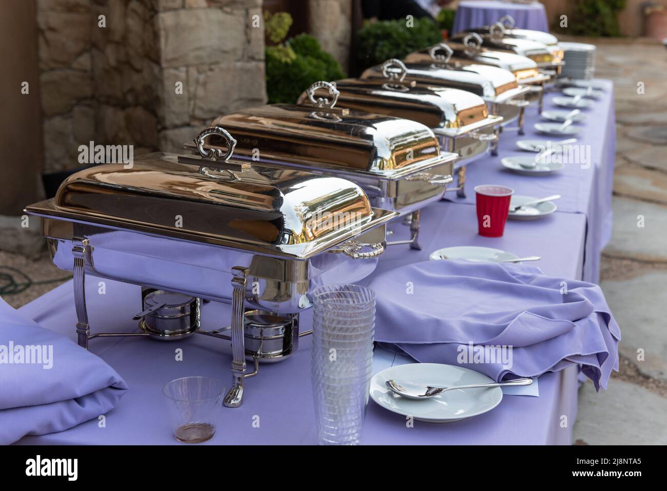 Shiny chaffing dishes are lined up on the banquet buffet table and ...